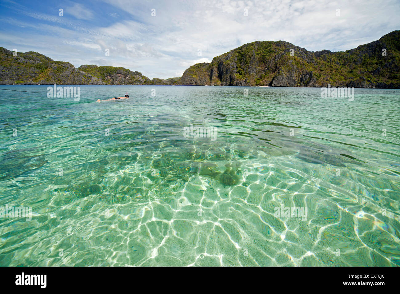 Snorkeller in the clear waters off Tapiutan Island, Bacuit archipelago ...
