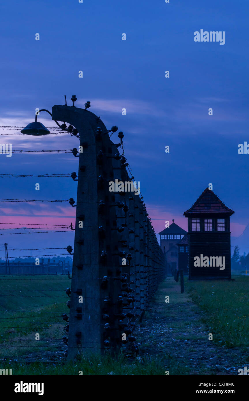 Barbed wire fence and watchtower at dusk, night, Auschwitz-Birkenau ...