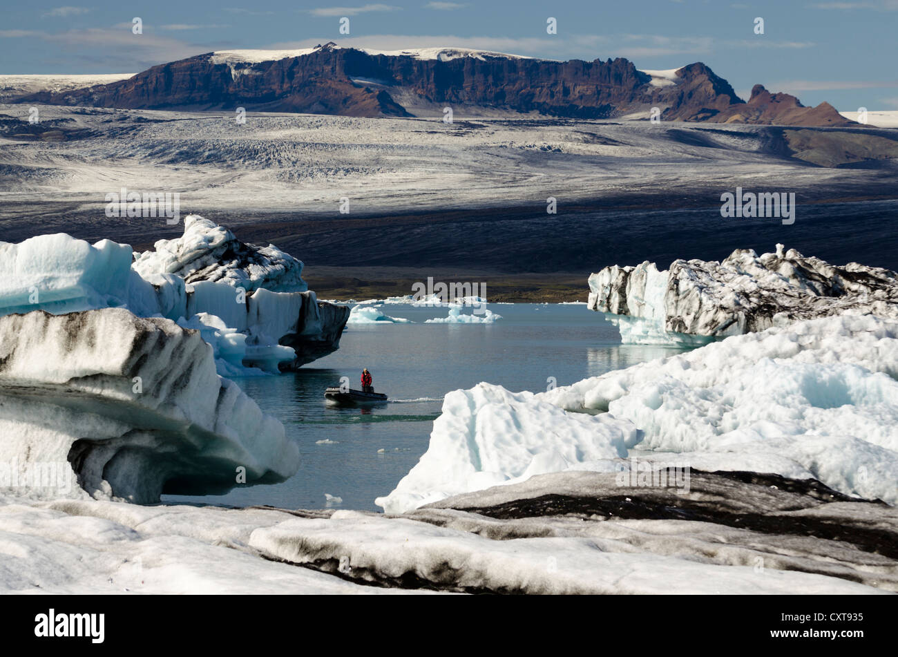Zodiac raft or inflatable boat, partly black ash-coloured icebergs ...