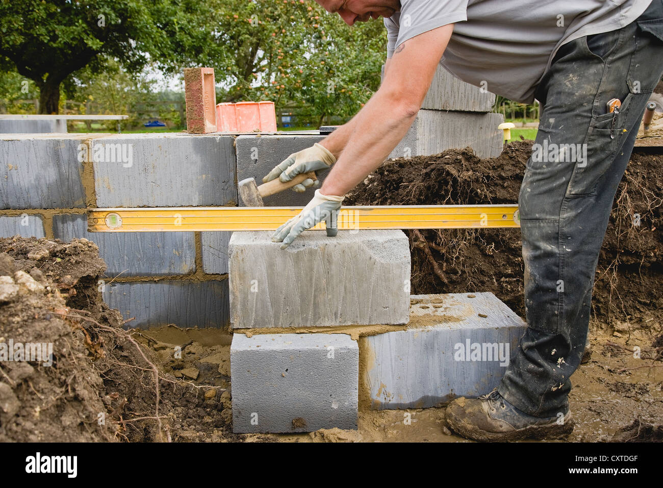 Bricklayer using Lump Hammer to level Concrete block when building ...