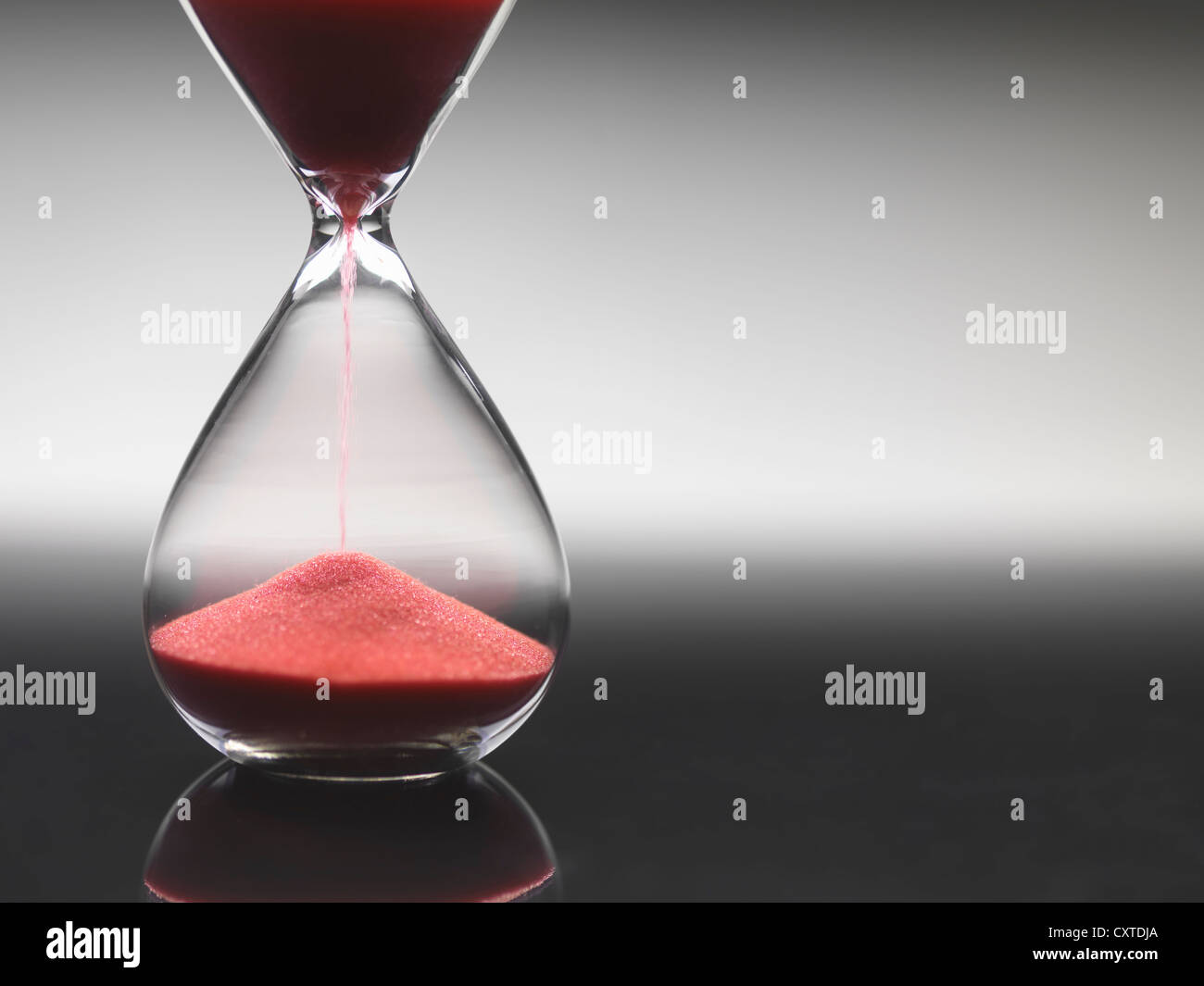 Pink sand pouring through hourglass Stock Photo - Alamy