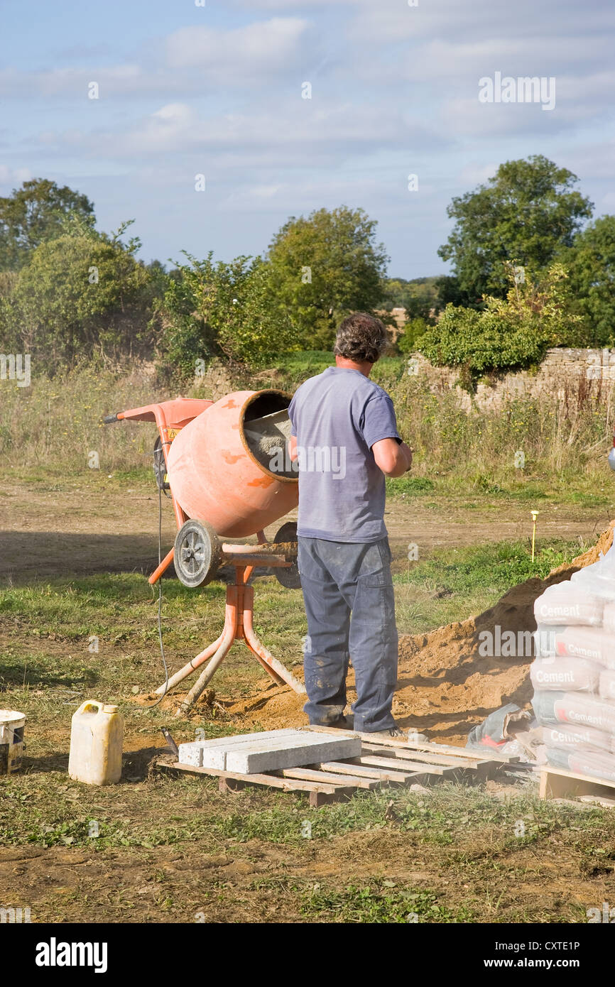 Labourer shoveling cement into a Cement Mixer Stock Photo - Alamy