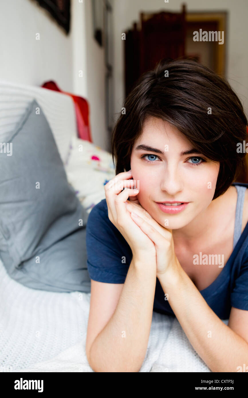 Woman resting on elbows on bed Stock Photo - Alamy