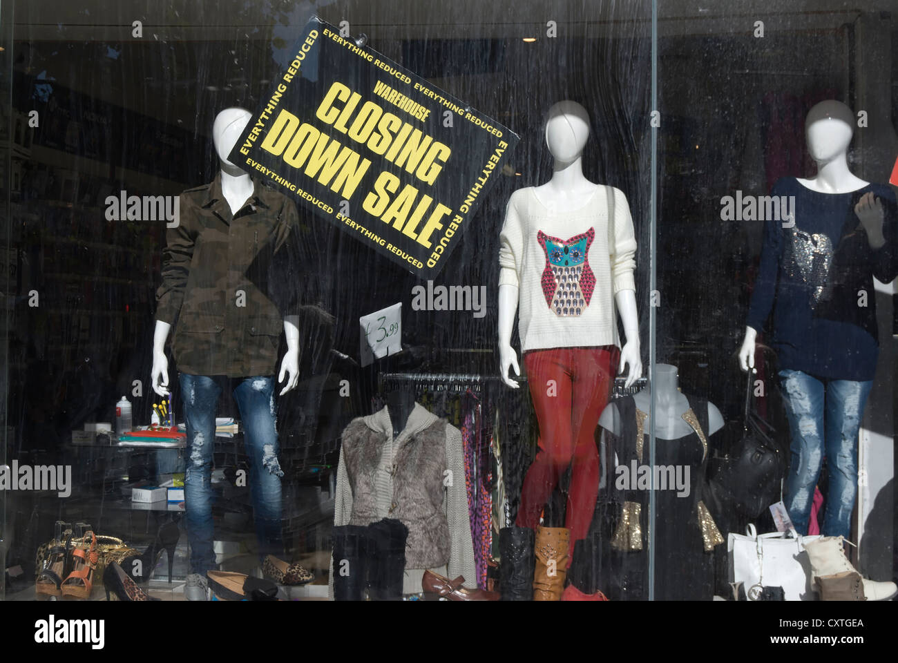 three shop dummies behind dirty shop window with closing down sale ...