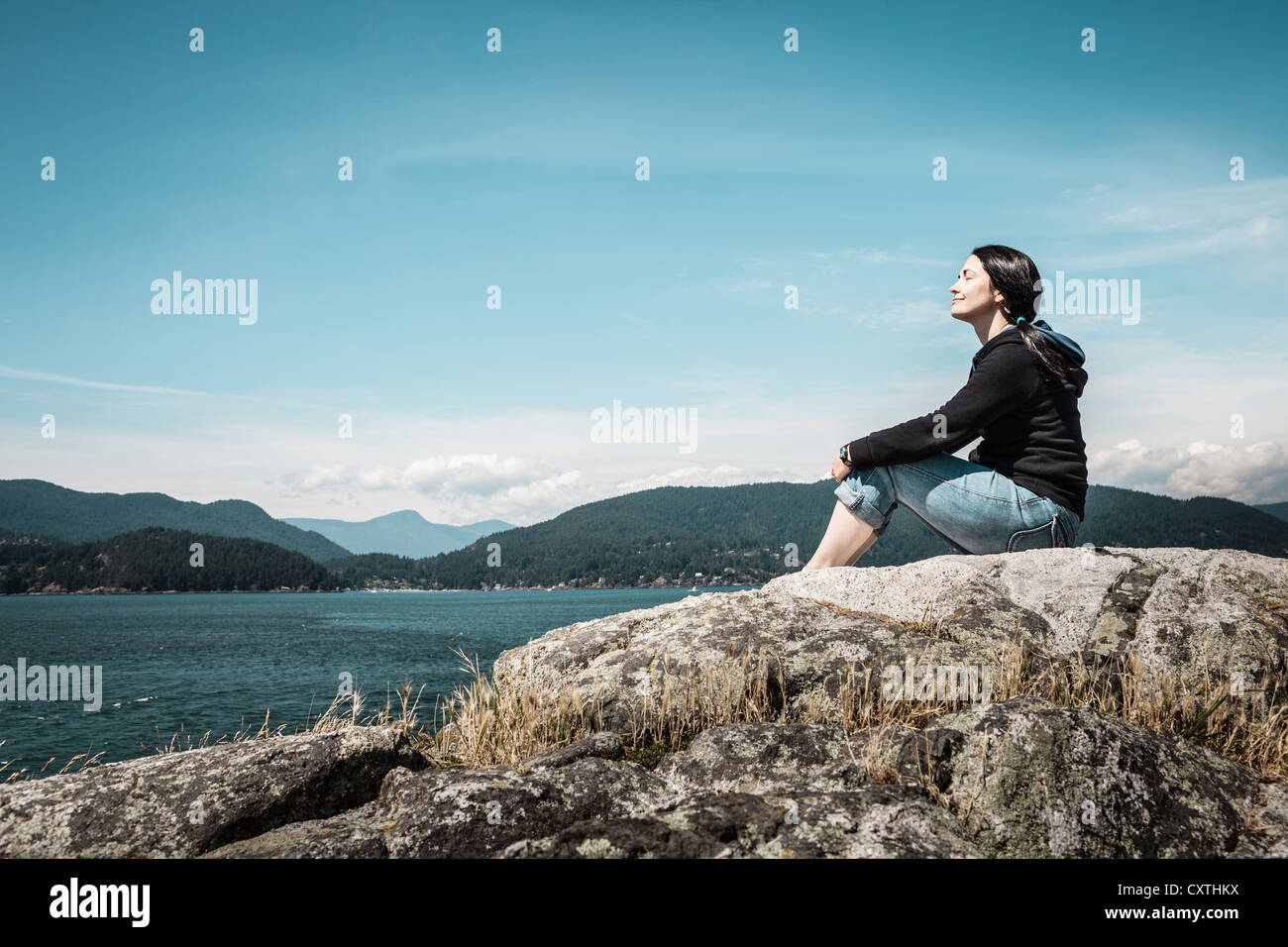 Woman relaxing by rural lake Stock Photo - Alamy