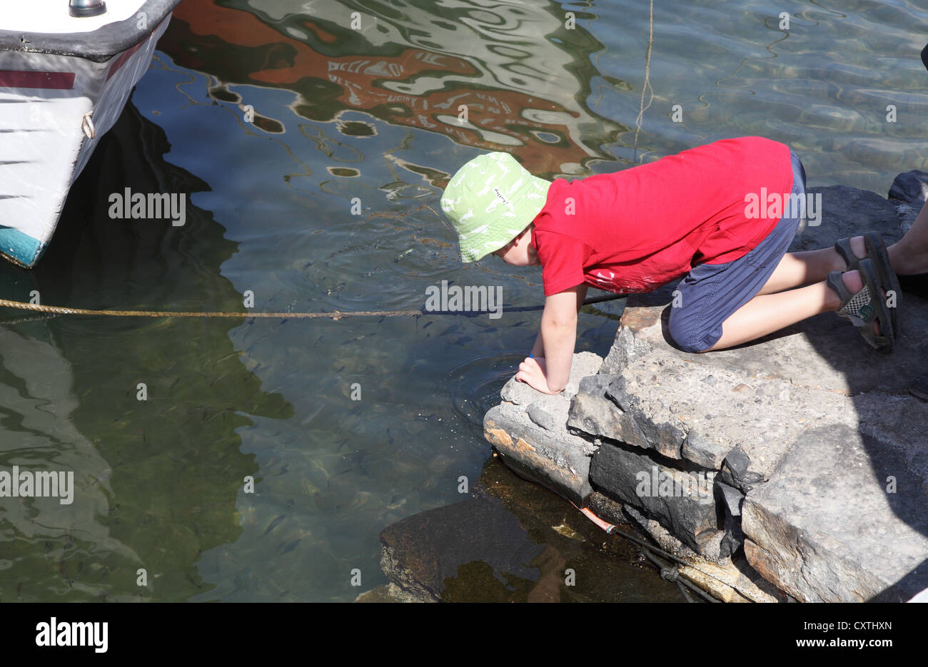 Young boy watching fish swimming in salt lake Agios Nikolaos Crete ...