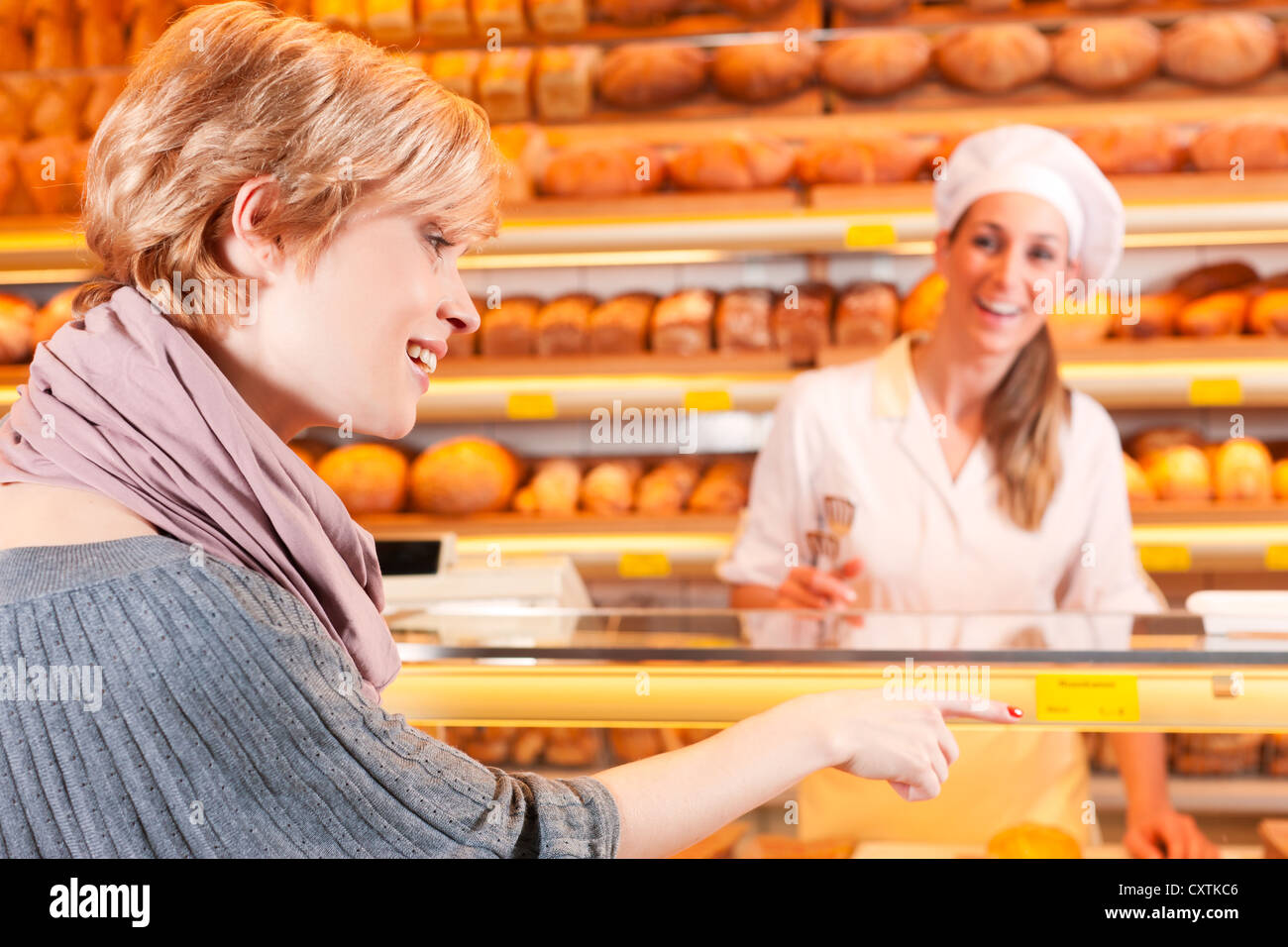 Female baker or saleswoman in her bakery with a female customer and ...