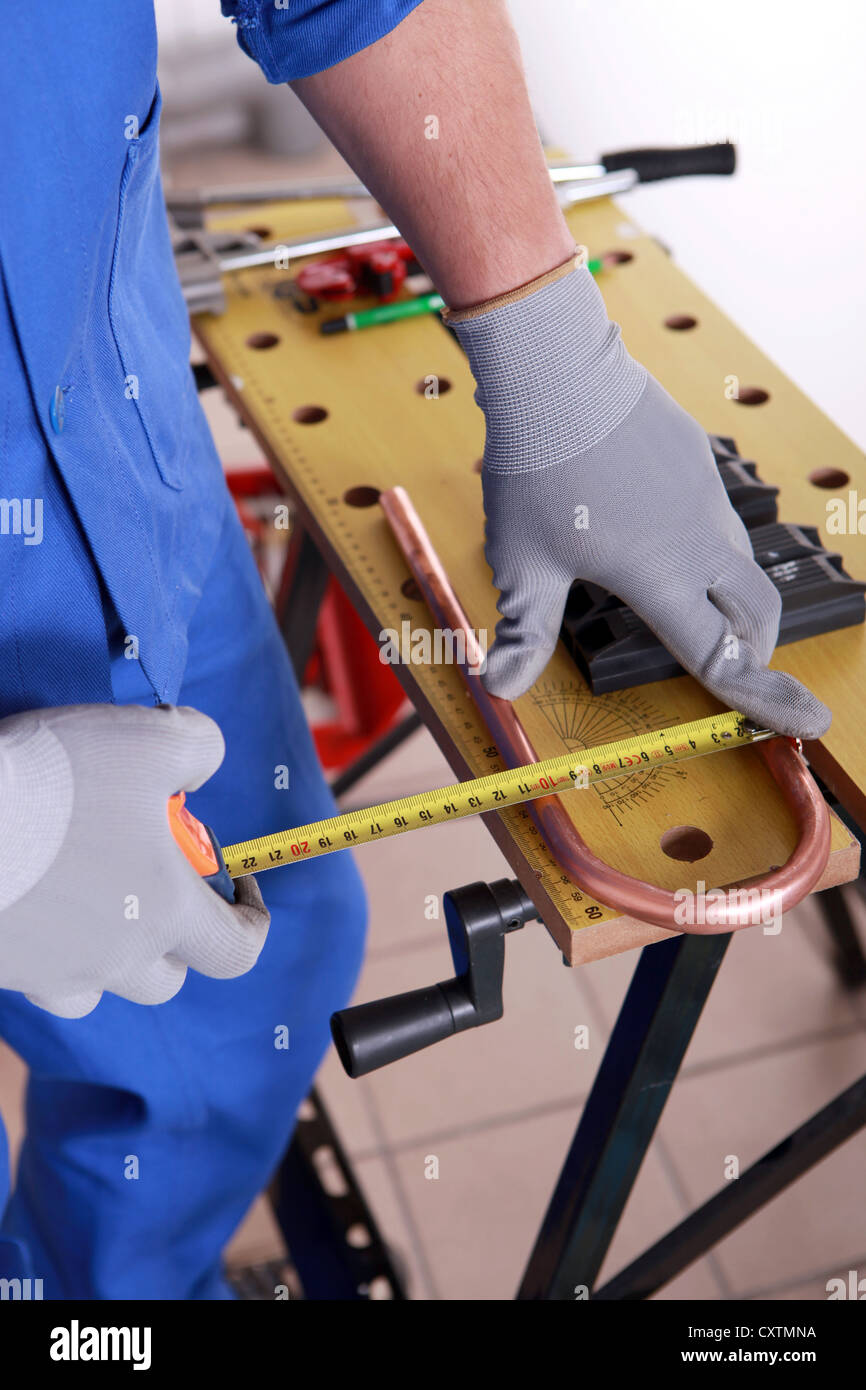 Labourer measuring bent copper pipe Stock Photo - Alamy