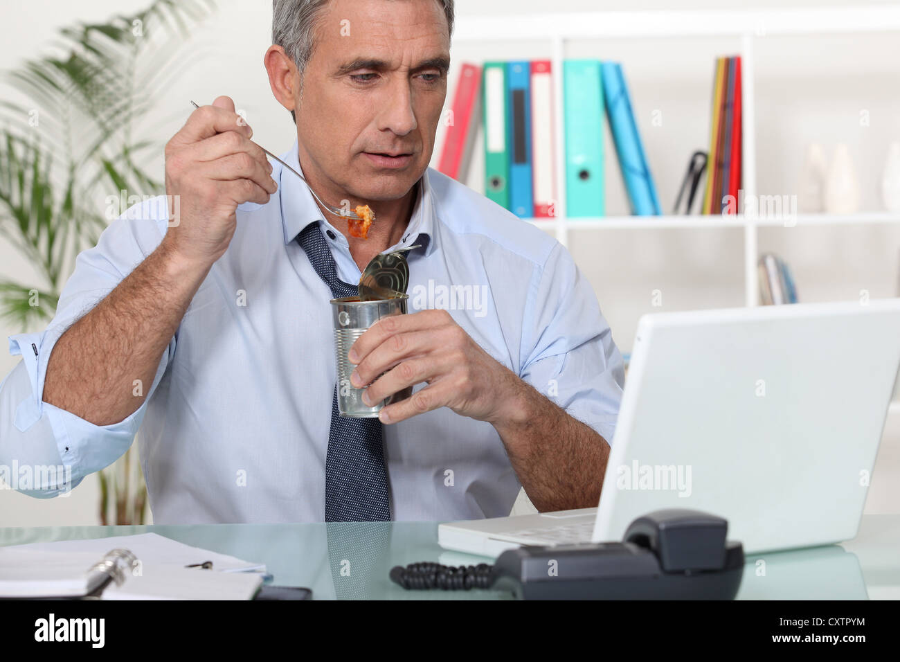 Businessman eating food from a tin Stock Photo - Alamy