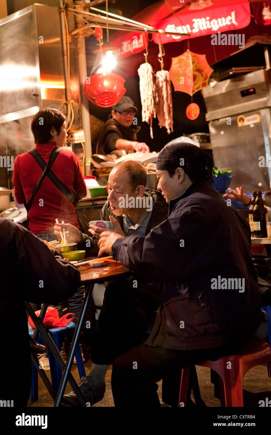 A table of men enjoy dinner at a street restaurant in Hong Kong's ...