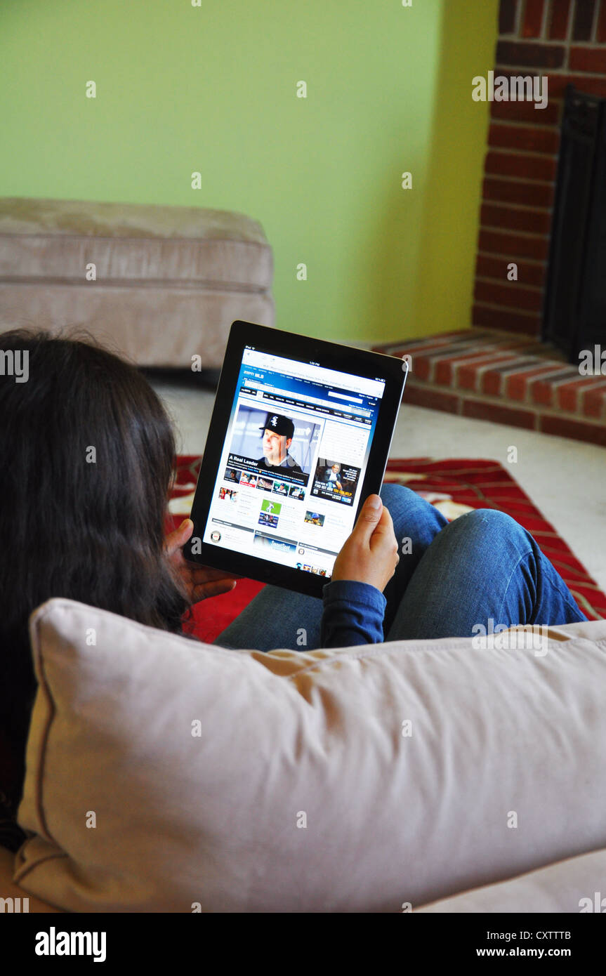 Young girl with iPad sitting on sofa at home. Major League Baseball ...