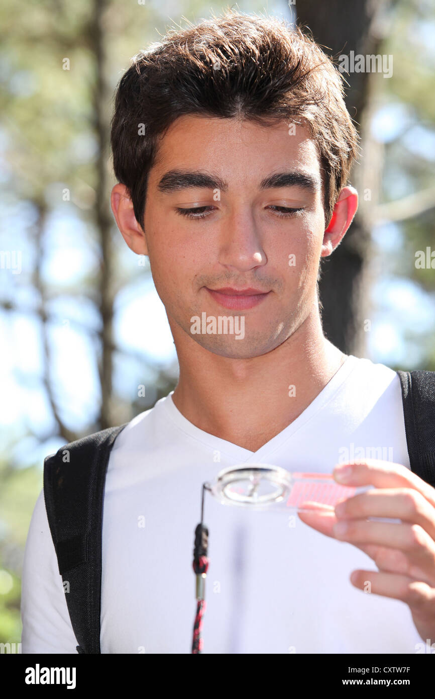 Man in a forest looking at his compass Stock Photo - Alamy