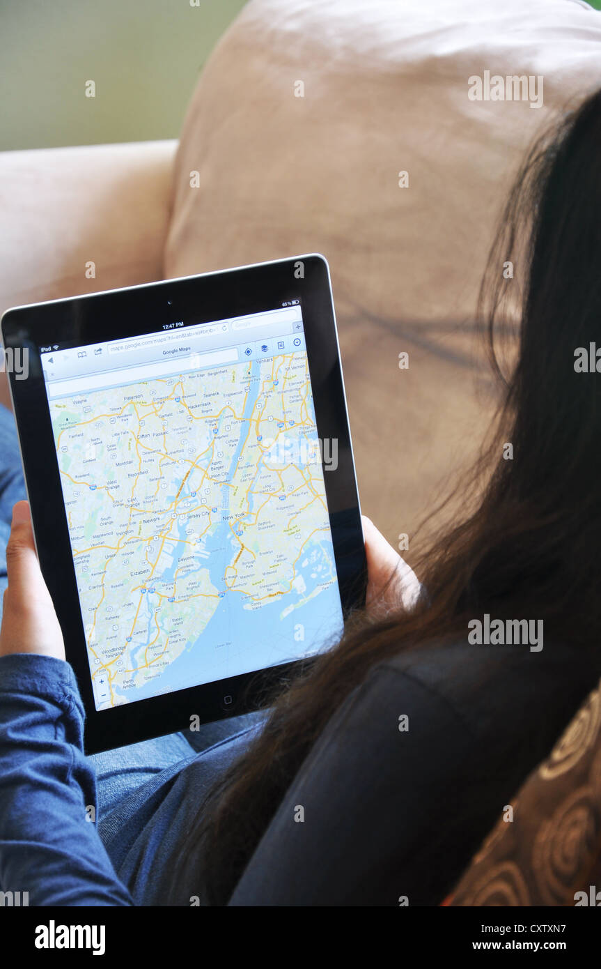Young girl with iPad sitting on sofa at home. New York City map shown ...