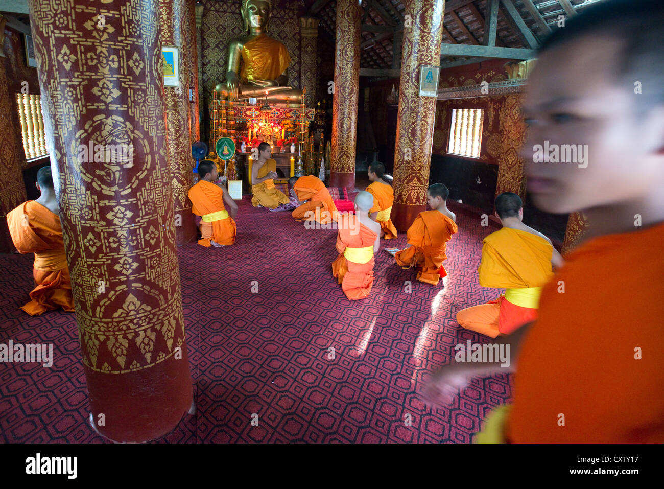 Monks sit in the meditation hall of Wat Xieng Thong. Luang Prabang ...