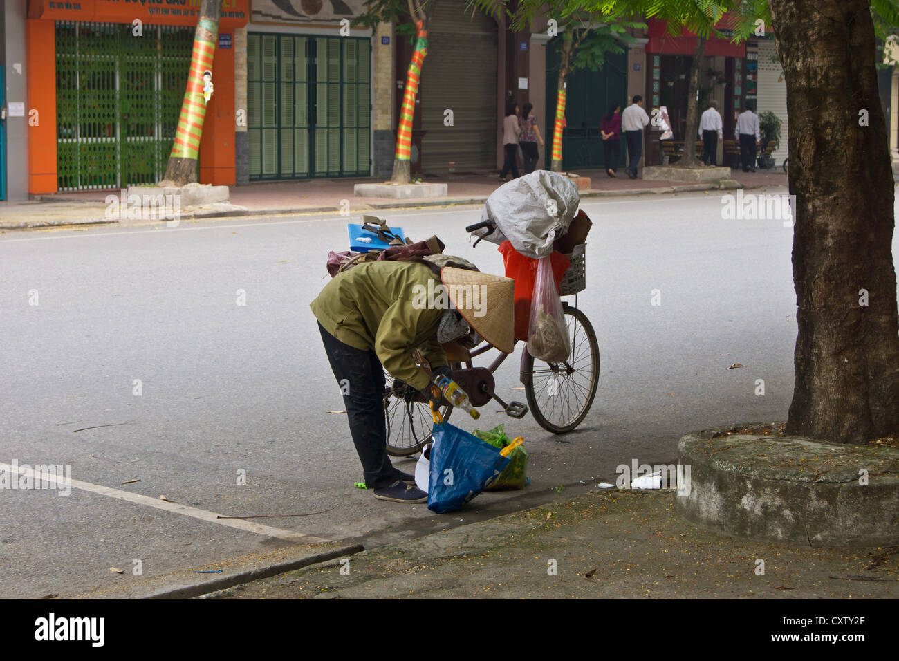 A Vietnamese lady stops to collect rubbish to be recycled on the road ...