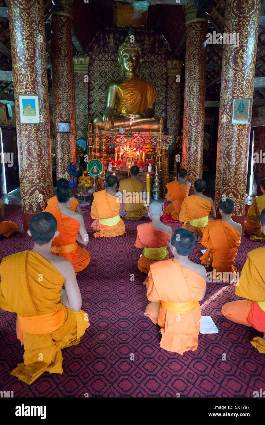 Monks sit in prayer in the meditation hall of Wat Xieng Thong. Luang ...