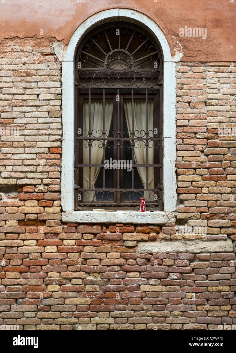 A Roman arched window with a wrought iron grille in front set in ...