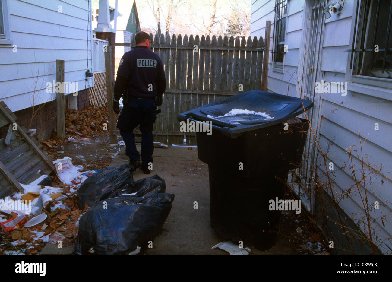 Detroit police Narcotics officer searches the side yard of a house ...