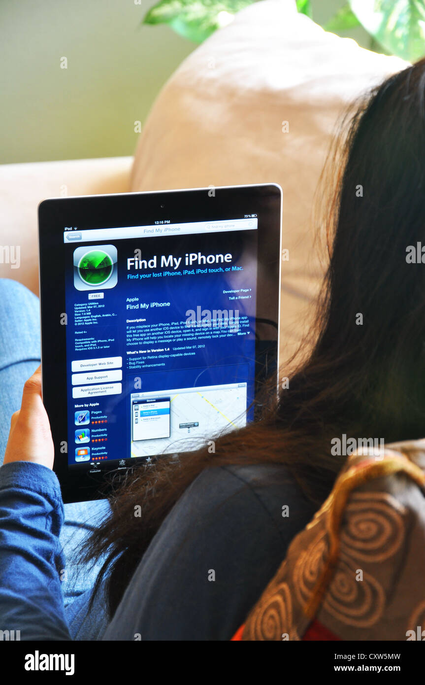 Young girl with iPad sitting on sofa at home. Find My iPhone app shown ...