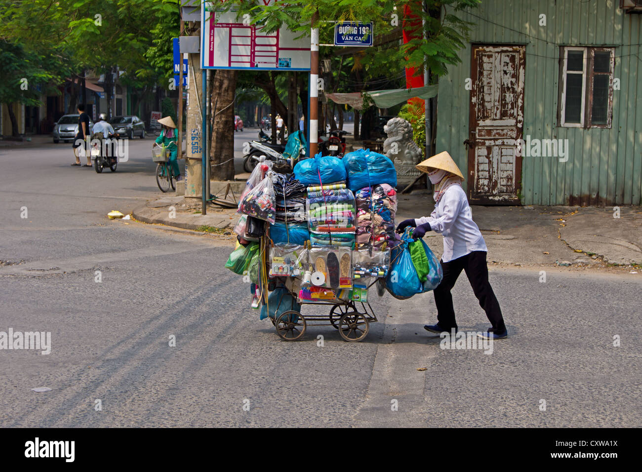 A Vietnamese lady pushing her cart of cloths and sandals for sale ...