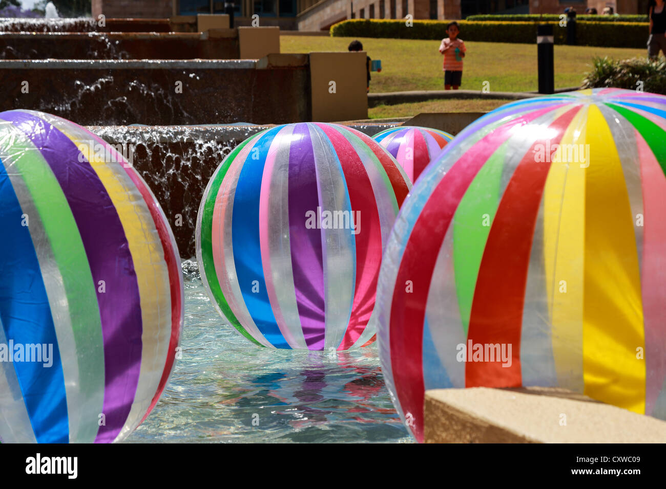 Colourful inflated transparent balls float in a man made pond in a pond ...