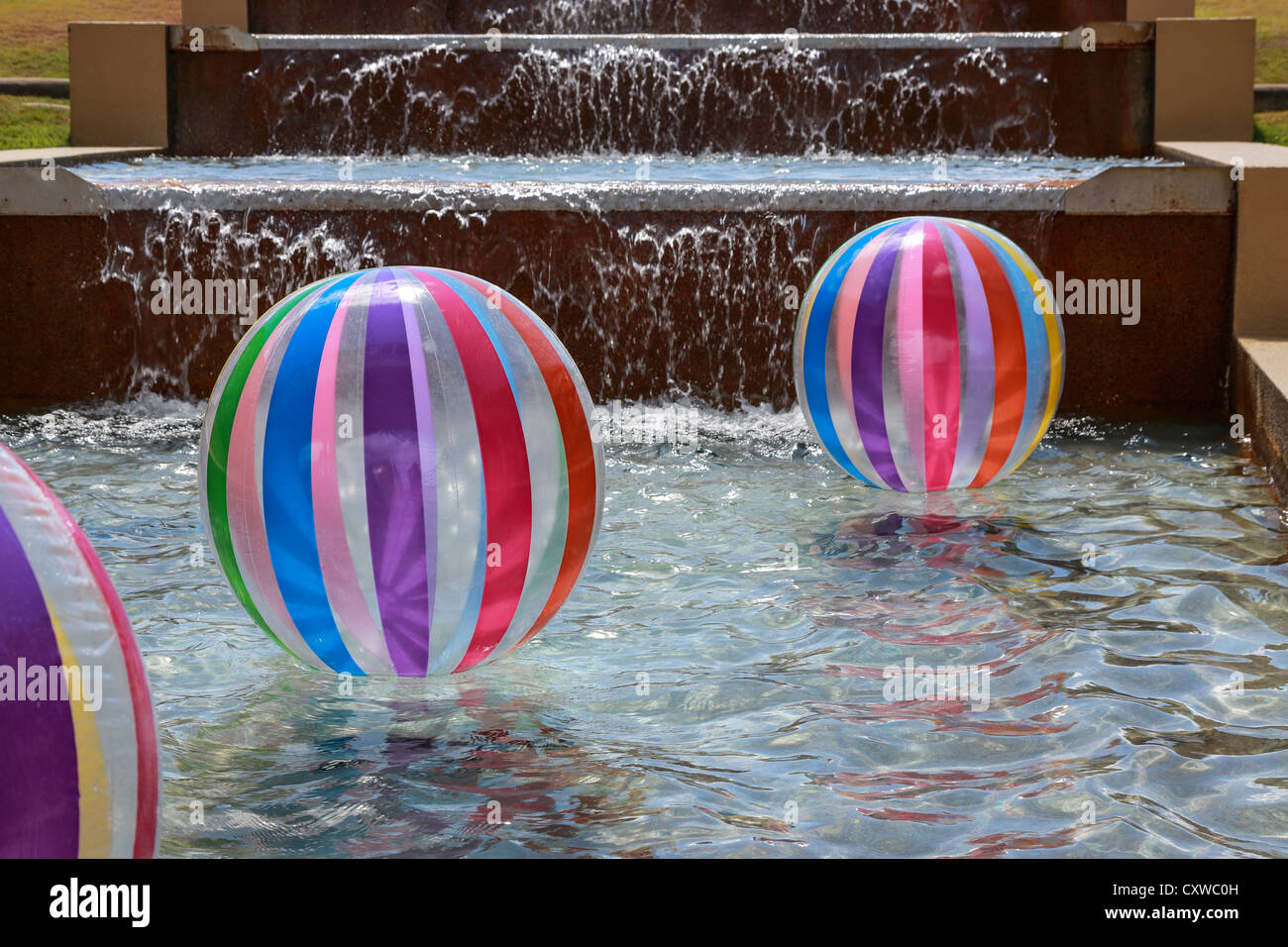 Colourful inflated transparent balls float in a man made pond in a pond ...