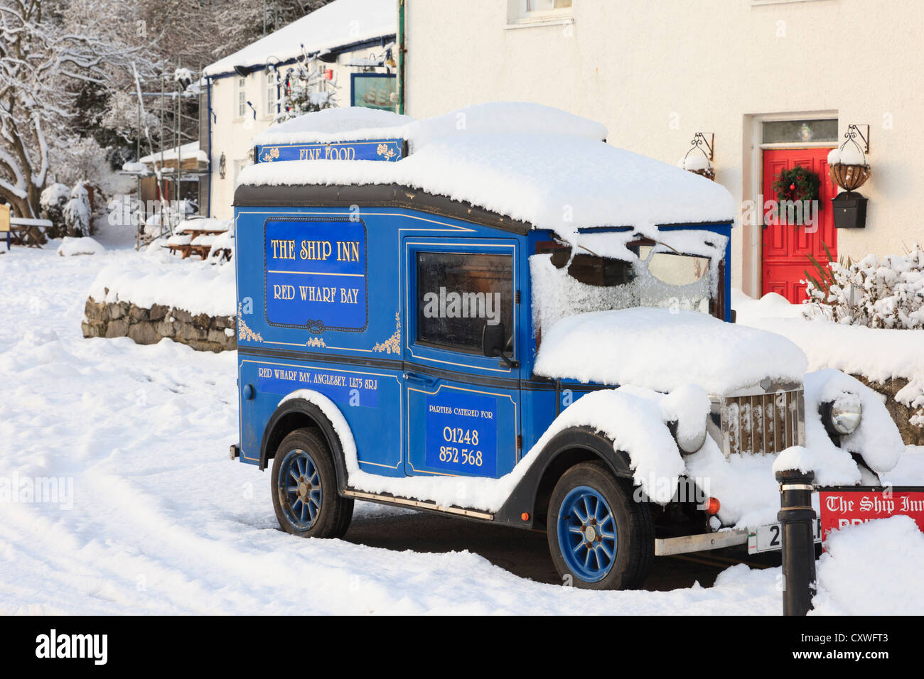 Vintage car advertising the Ship Inn village pub in winter snow in Red ...