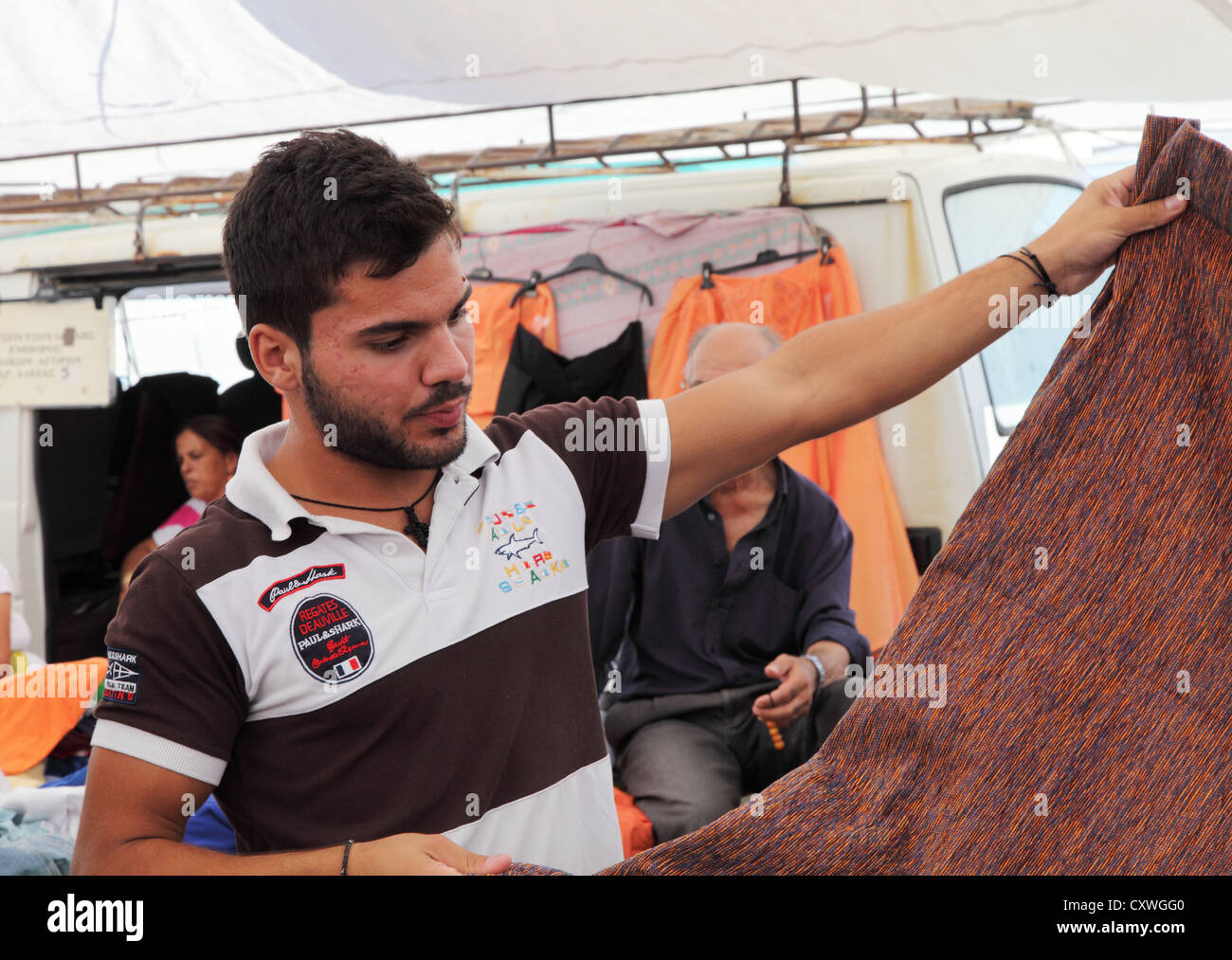 Market trader holding or demonstrating fabric open air street market ...
