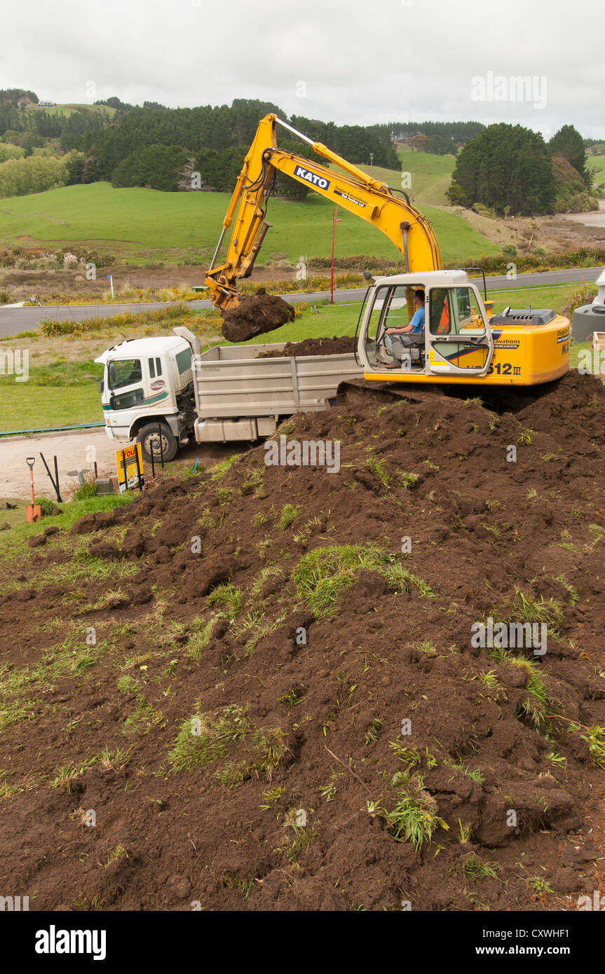 Man excavating soil for new home on steep sloping section, surrounded ...