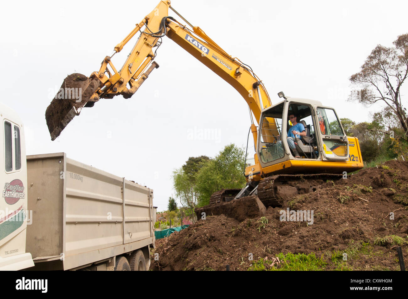 Man excavating soil for new home on steep sloping section, surrounded ...