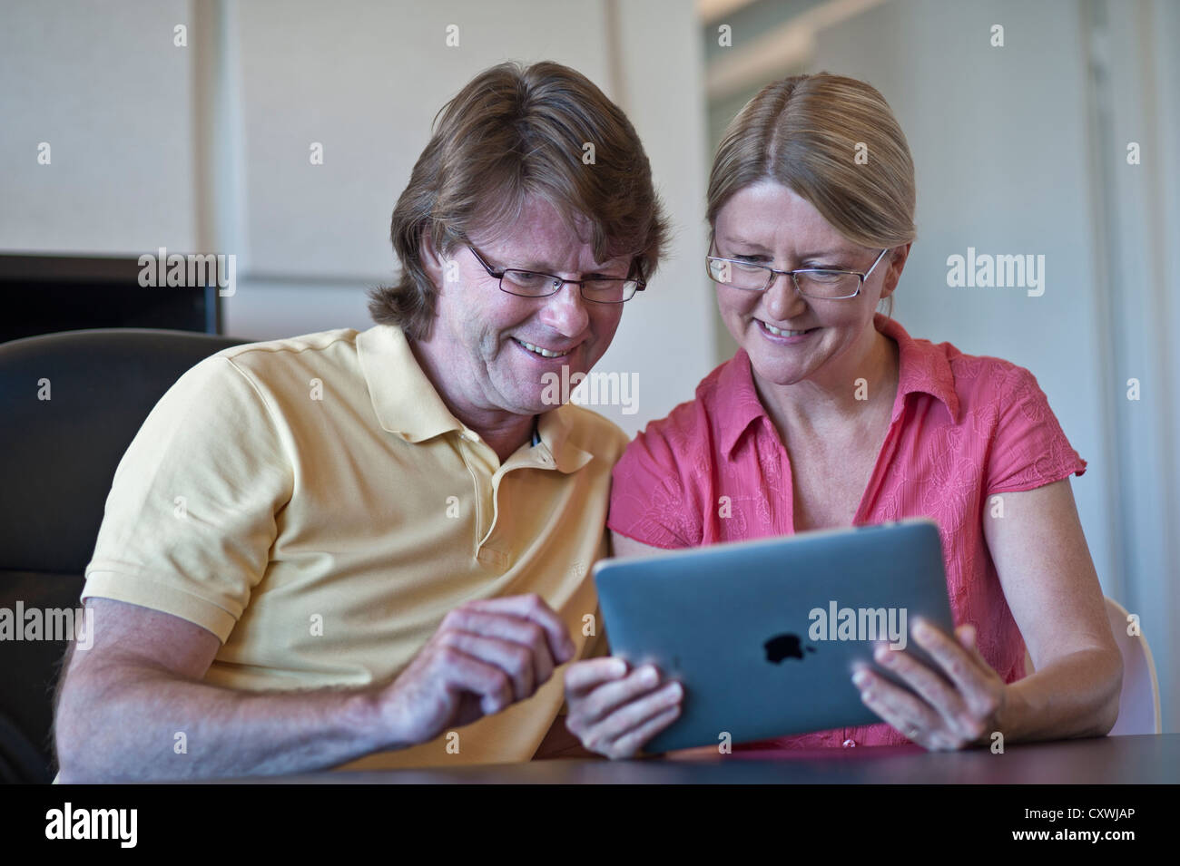 Attractive couple at home using their iPad tablet computer together in ...
