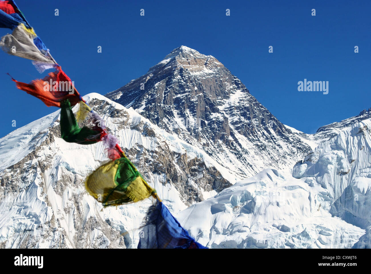 View of Mount Everest with blue sky backdrop and Buddhist prayer flags ...