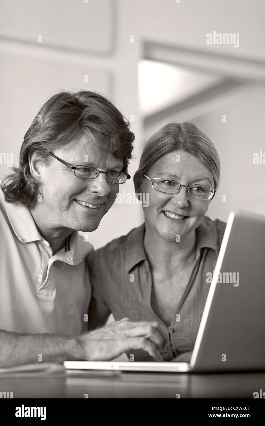 Attractive couple at home using their laptop computer together, in ...
