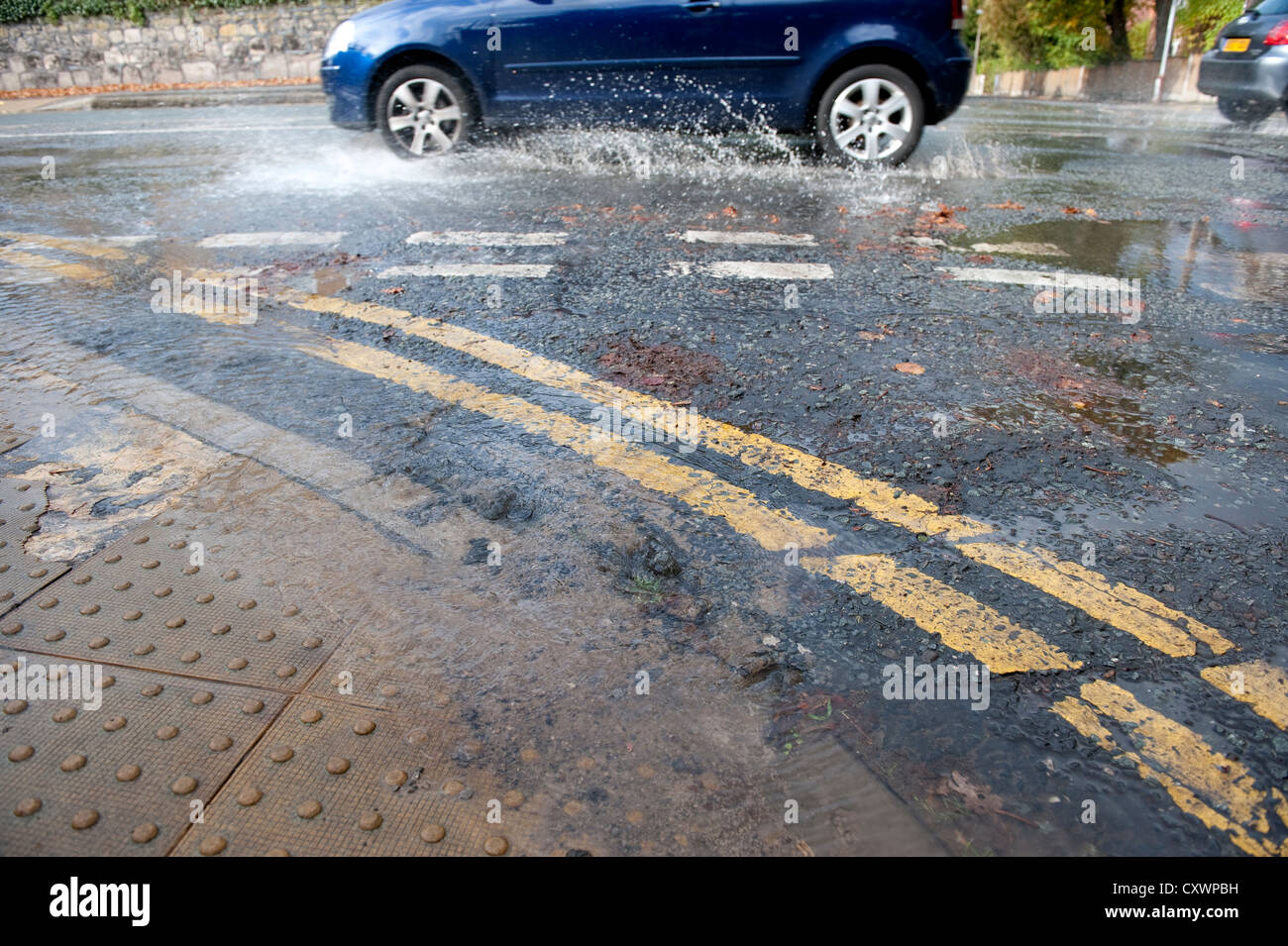 Burst water main pipe flooding road with cars going past Stock Photo ...