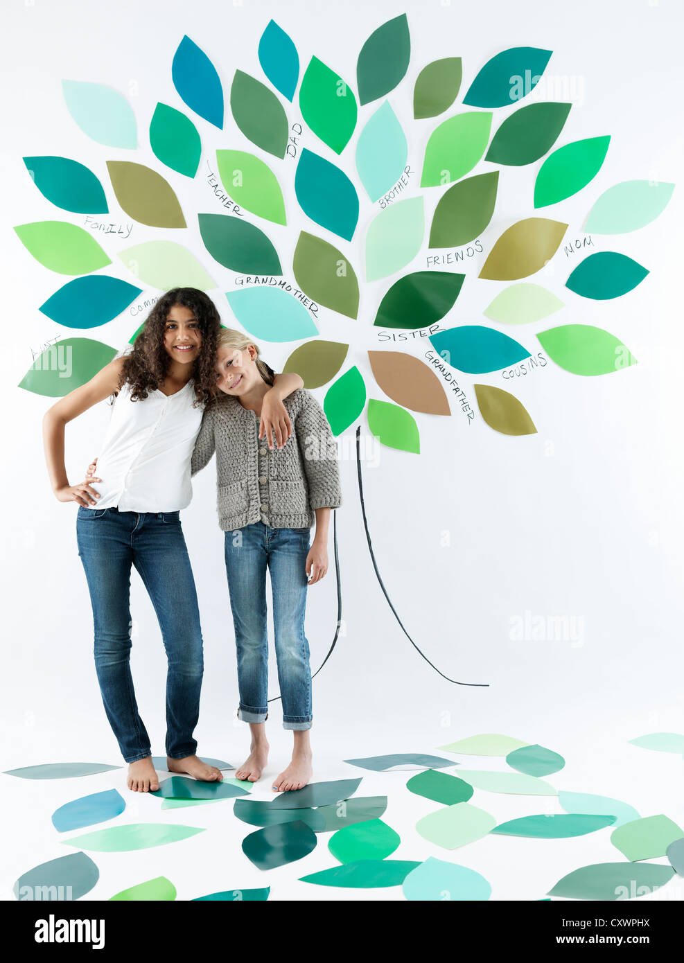 Girls standing under tree on wall Stock Photo - Alamy