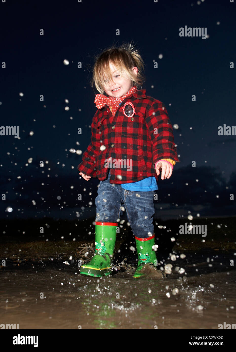 Girl splashing in puddle at night Stock Photo - Alamy
