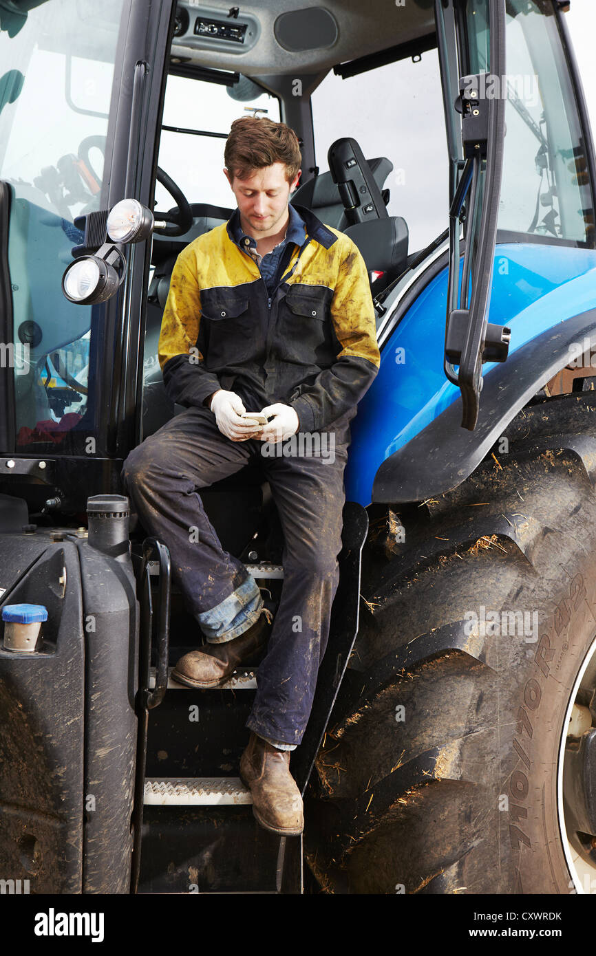 Farmer using cell phone on tractor Stock Photo - Alamy