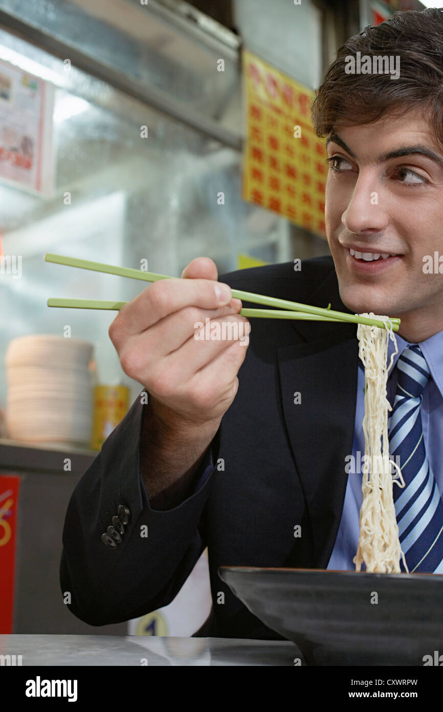 Businessman eating noodles in cafe Stock Photo - Alamy