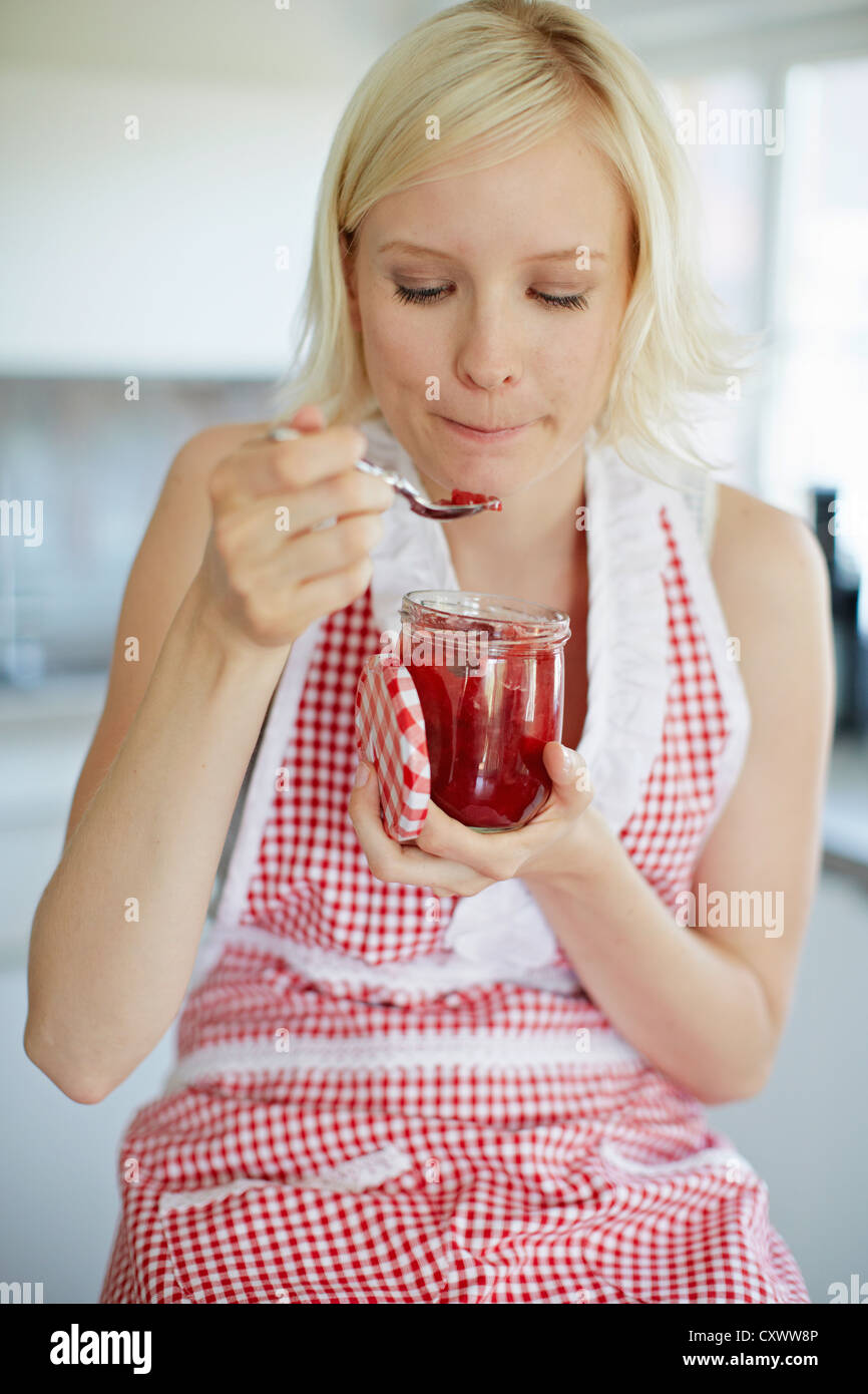 Woman eating jelly from jar in kitchen Stock Photo - Alamy