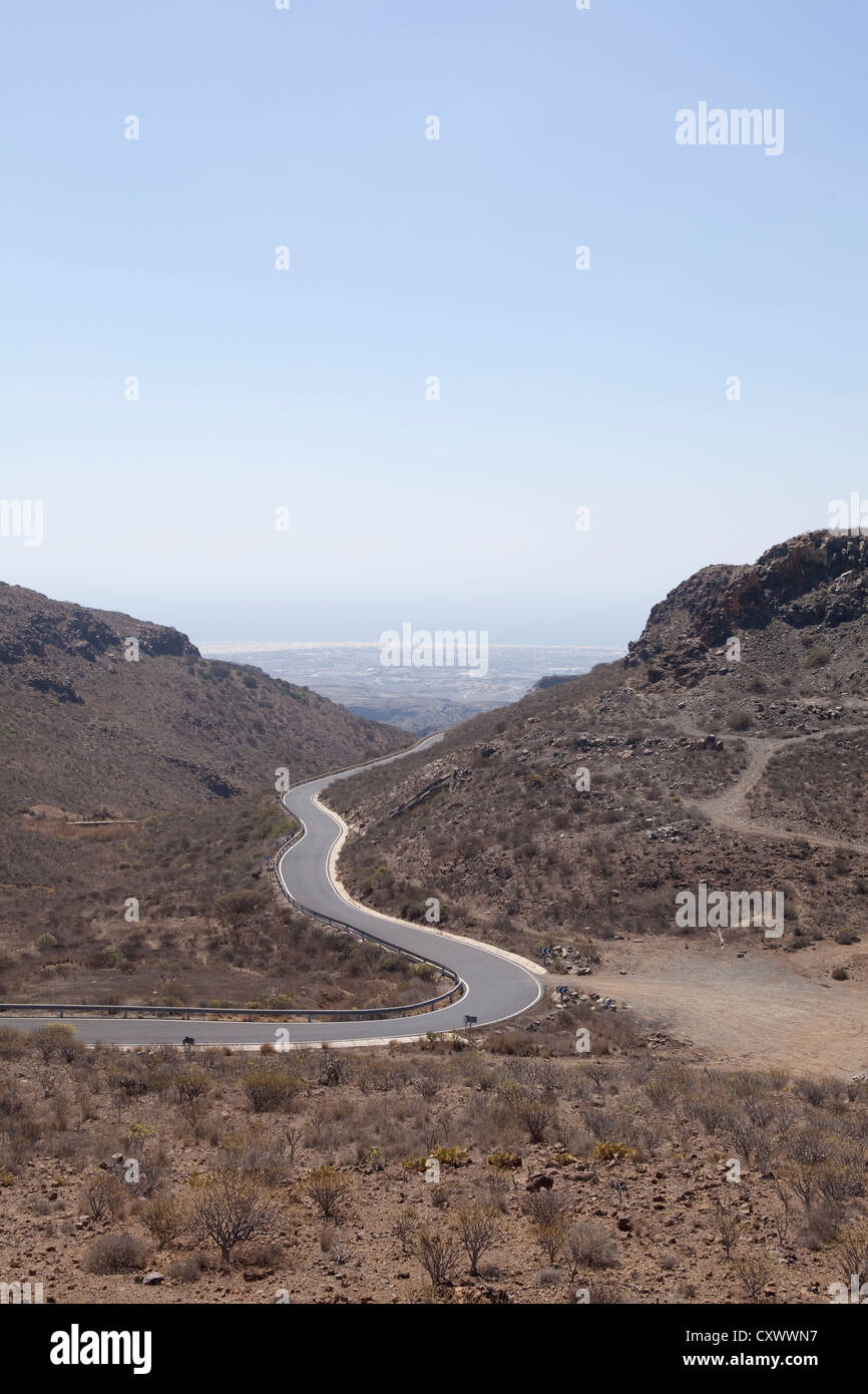 Downhill road winding through mountains Stock Photo - Alamy