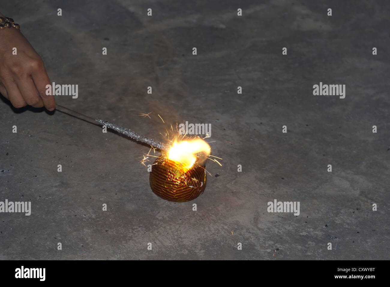 Lighting a firecracker using a sparkler as part of Diwali celebrations ...