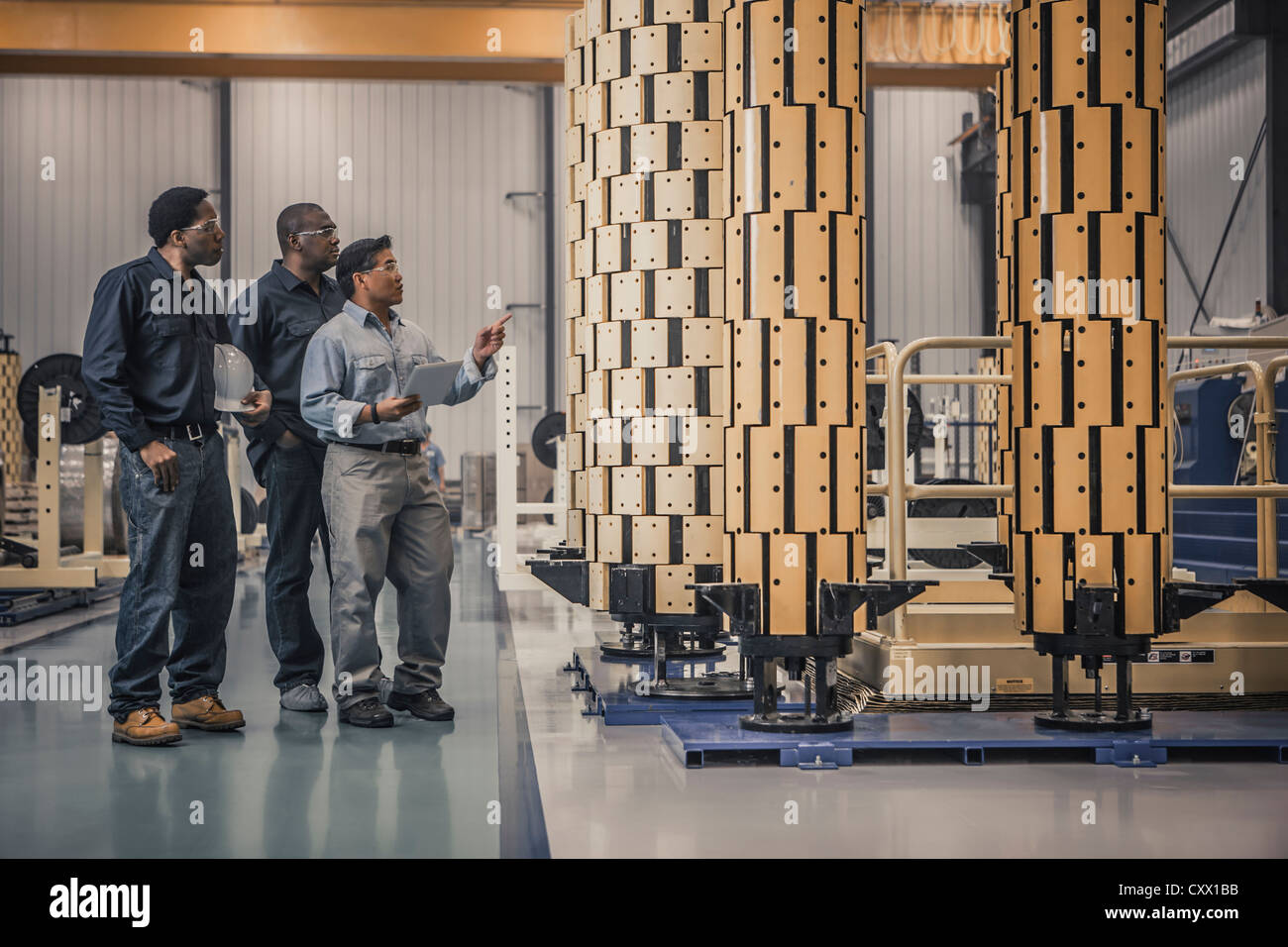Workers looking at equipment in factory Stock Photo - Alamy