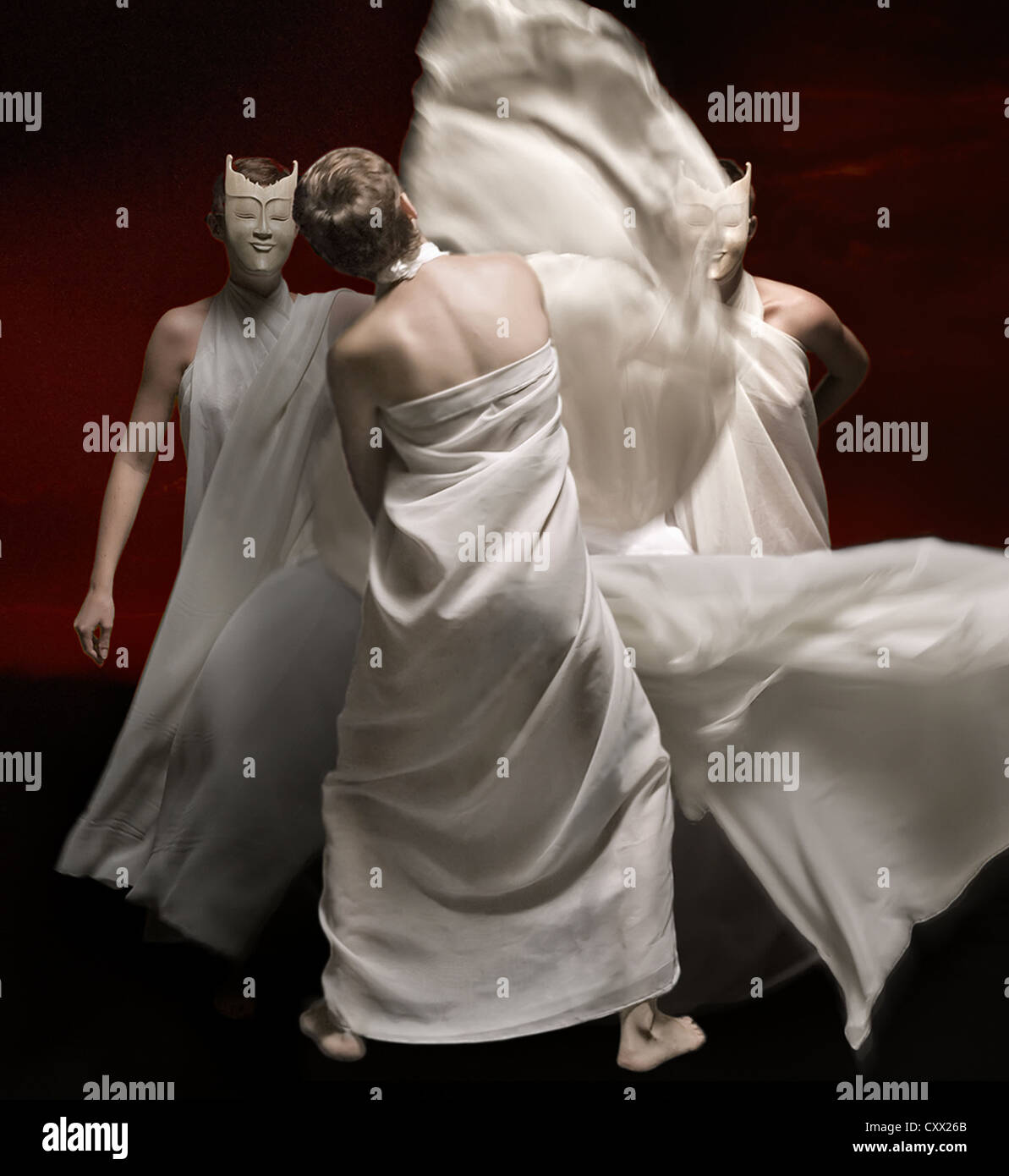 Dancers in flowing gowns perform under dramatic lighting amid a black ...