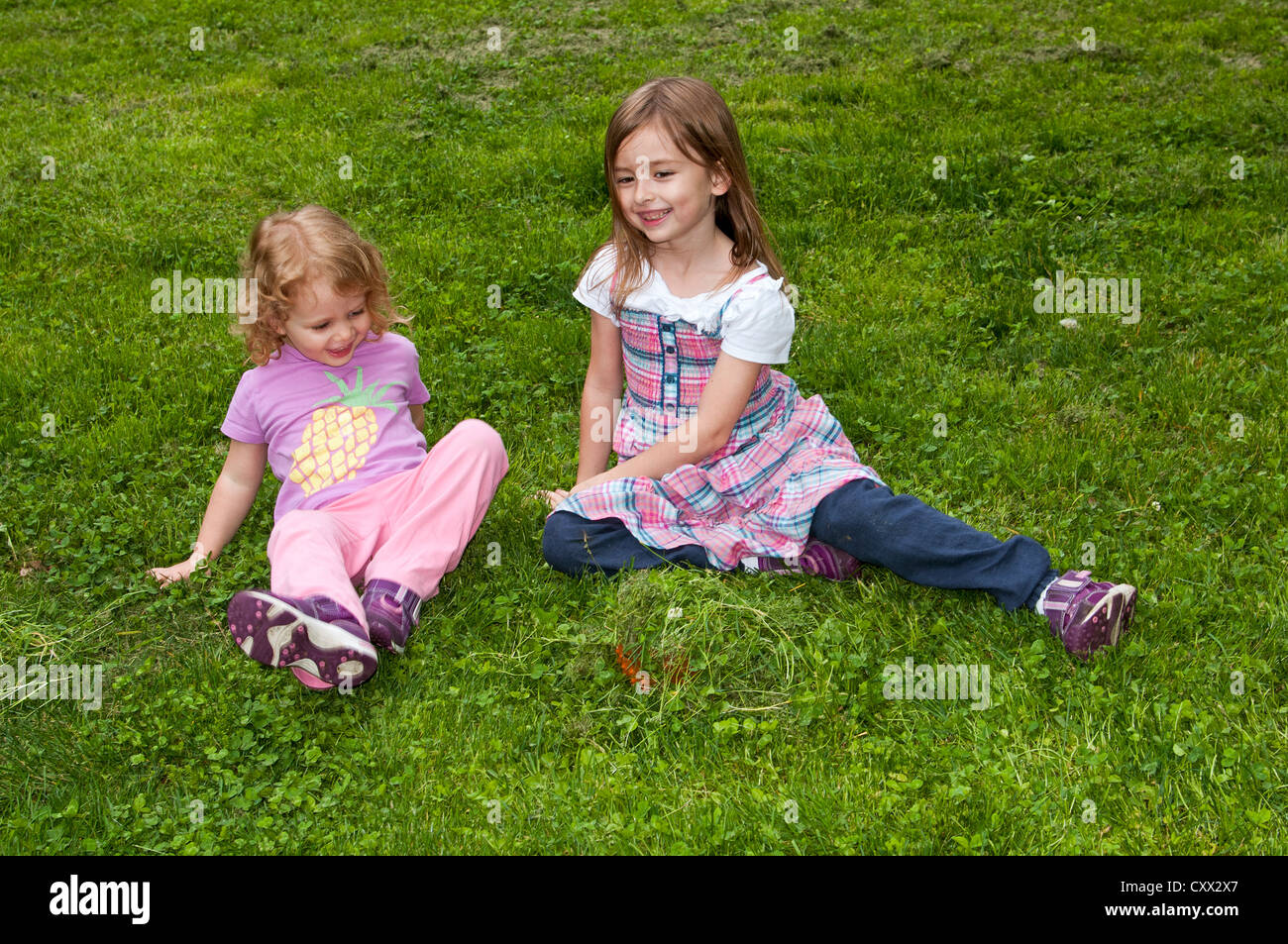 Two young girls playing on the grass Stock Photo - Alamy