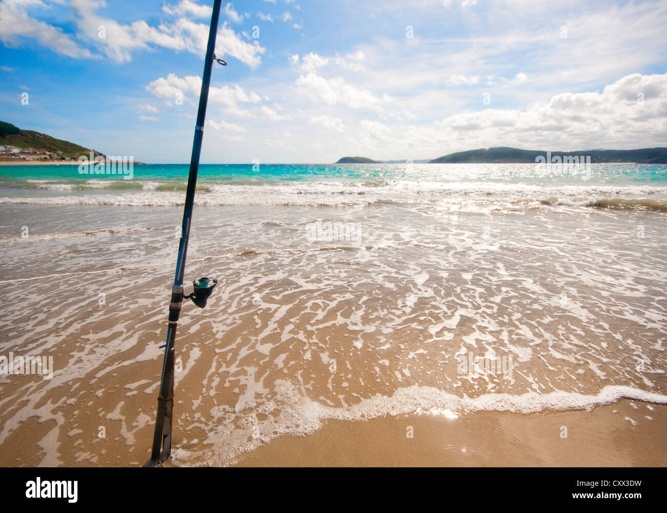 Fixed fishing rod set up on a beach near the surf on the incoming tide ...