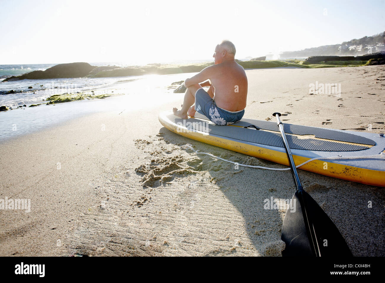 Caucasian man sitting on paddleboard Stock Photo - Alamy