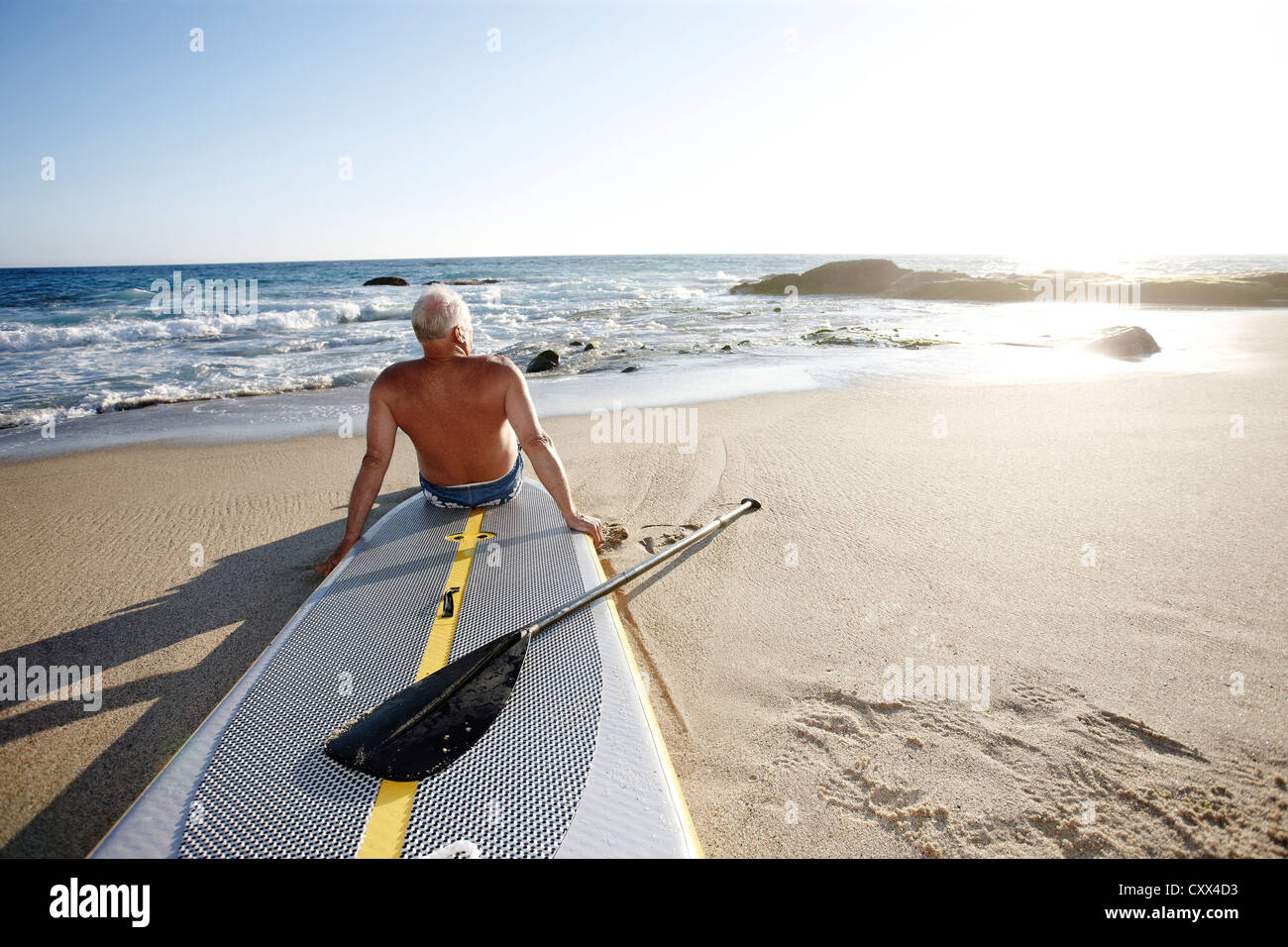 Caucasian man sitting on paddleboard Stock Photo - Alamy