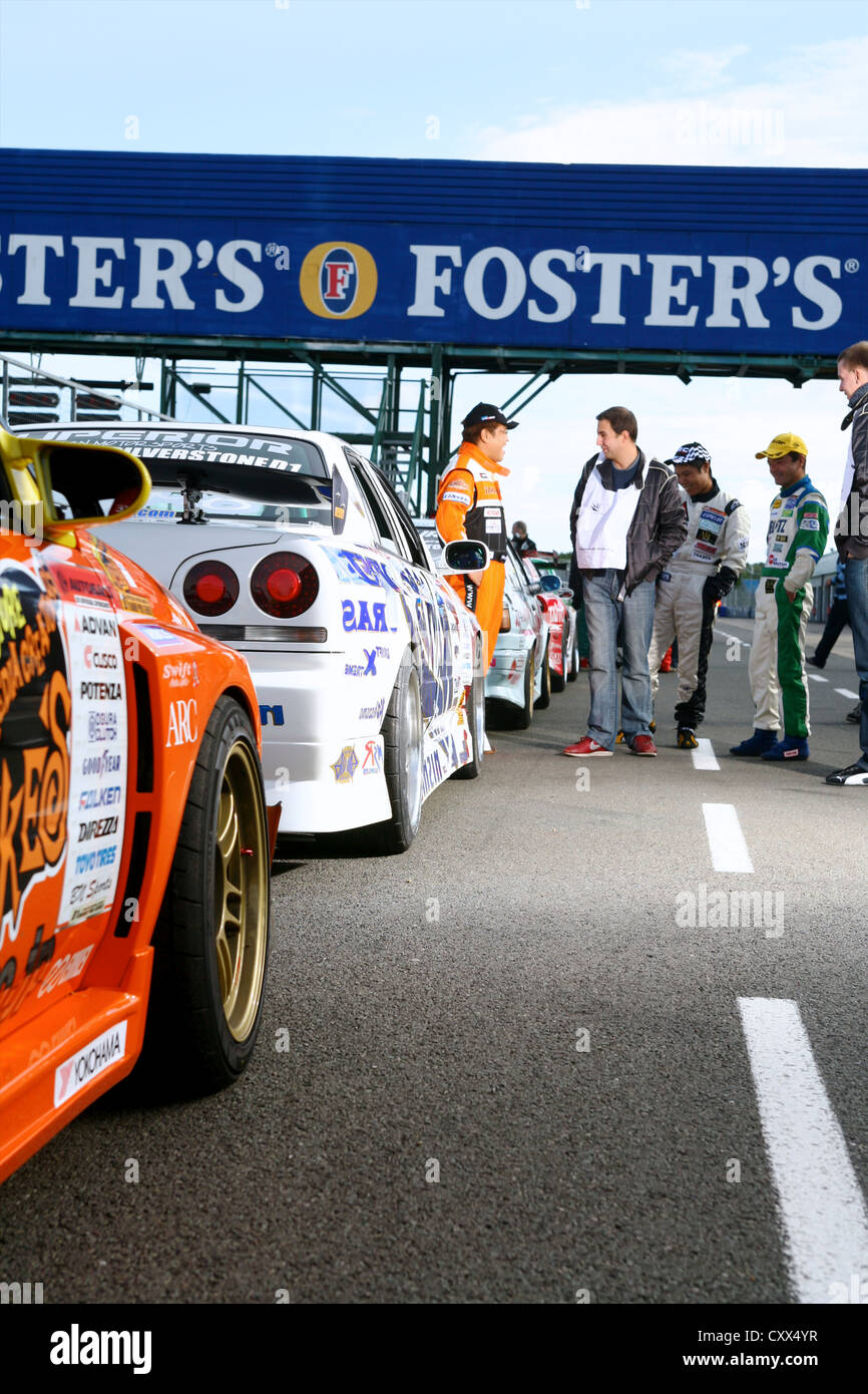 Race cars lined up with drivers talking Stock Photo - Alamy