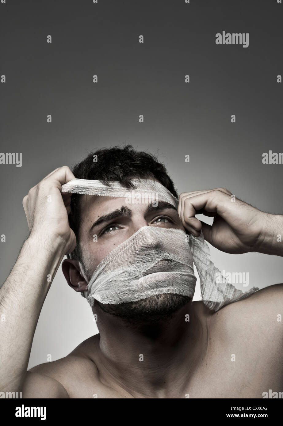 Man removing bandage from his face Stock Photo - Alamy