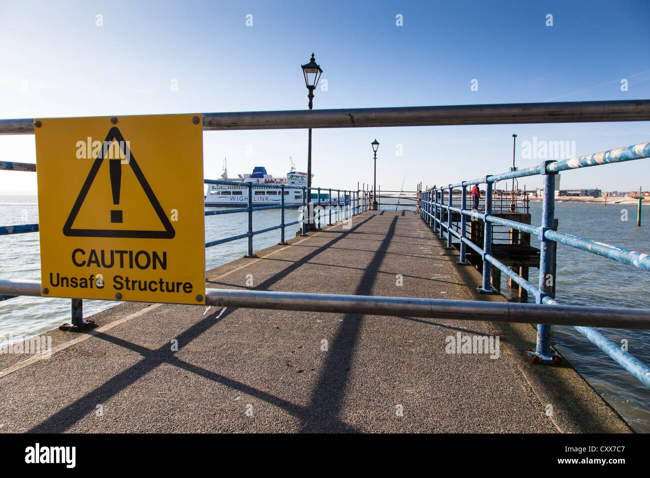 A yellow warning sign marks the beginning of a pier, beyond a Wightlink ...